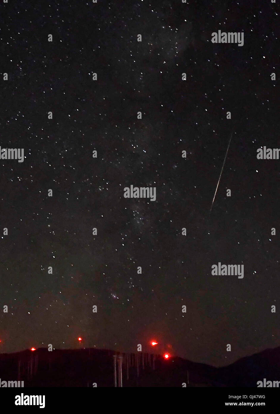 Meteors shoot across the night skies over a wind mill farm during the ...