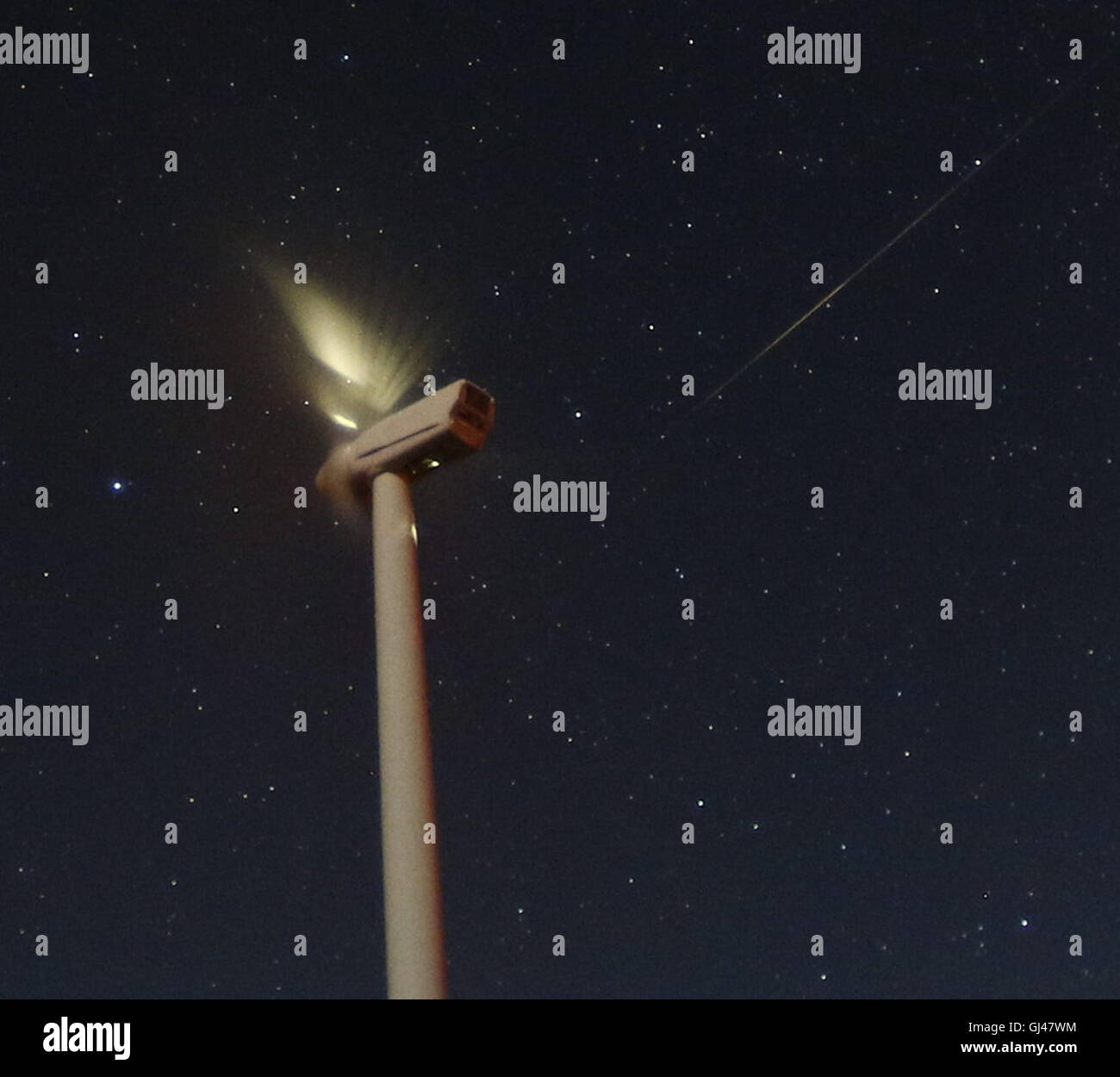 Meteors shoot across the night skies over a wind mill farm during the ...
