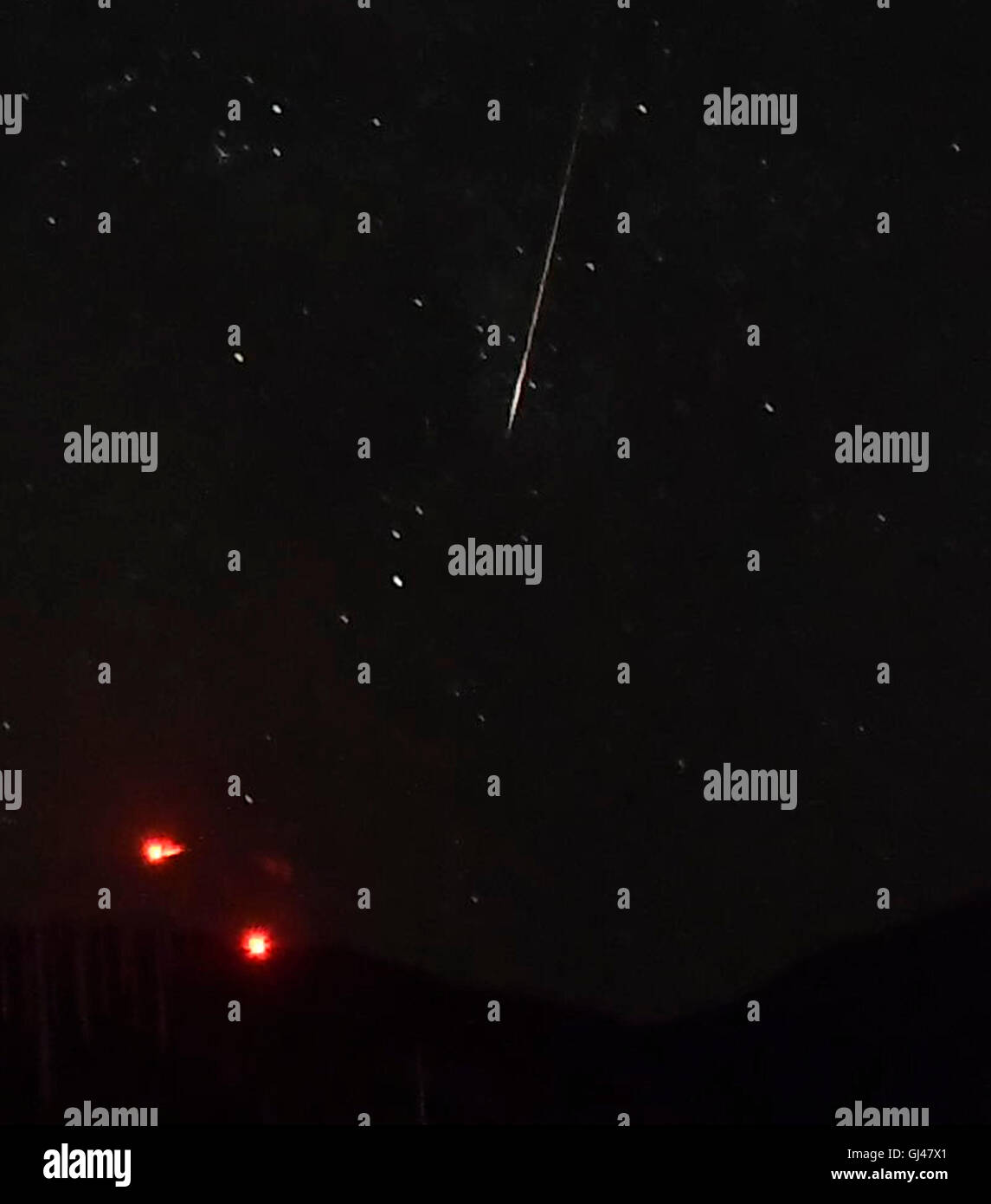 Meteors shoot across the night skies over a wind mill farm during the ...