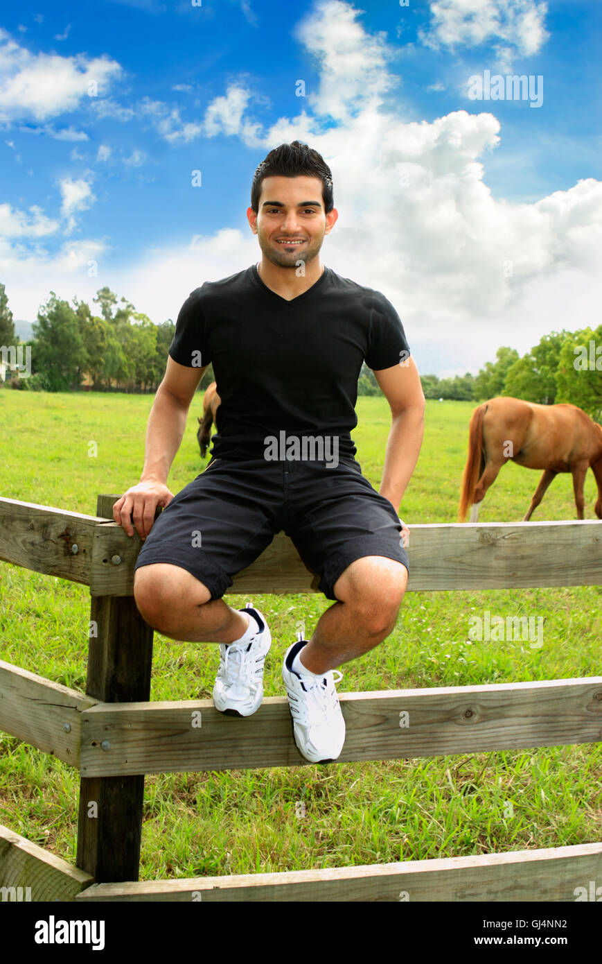 Man sitting on fence countryside Stock Photo - Alamy