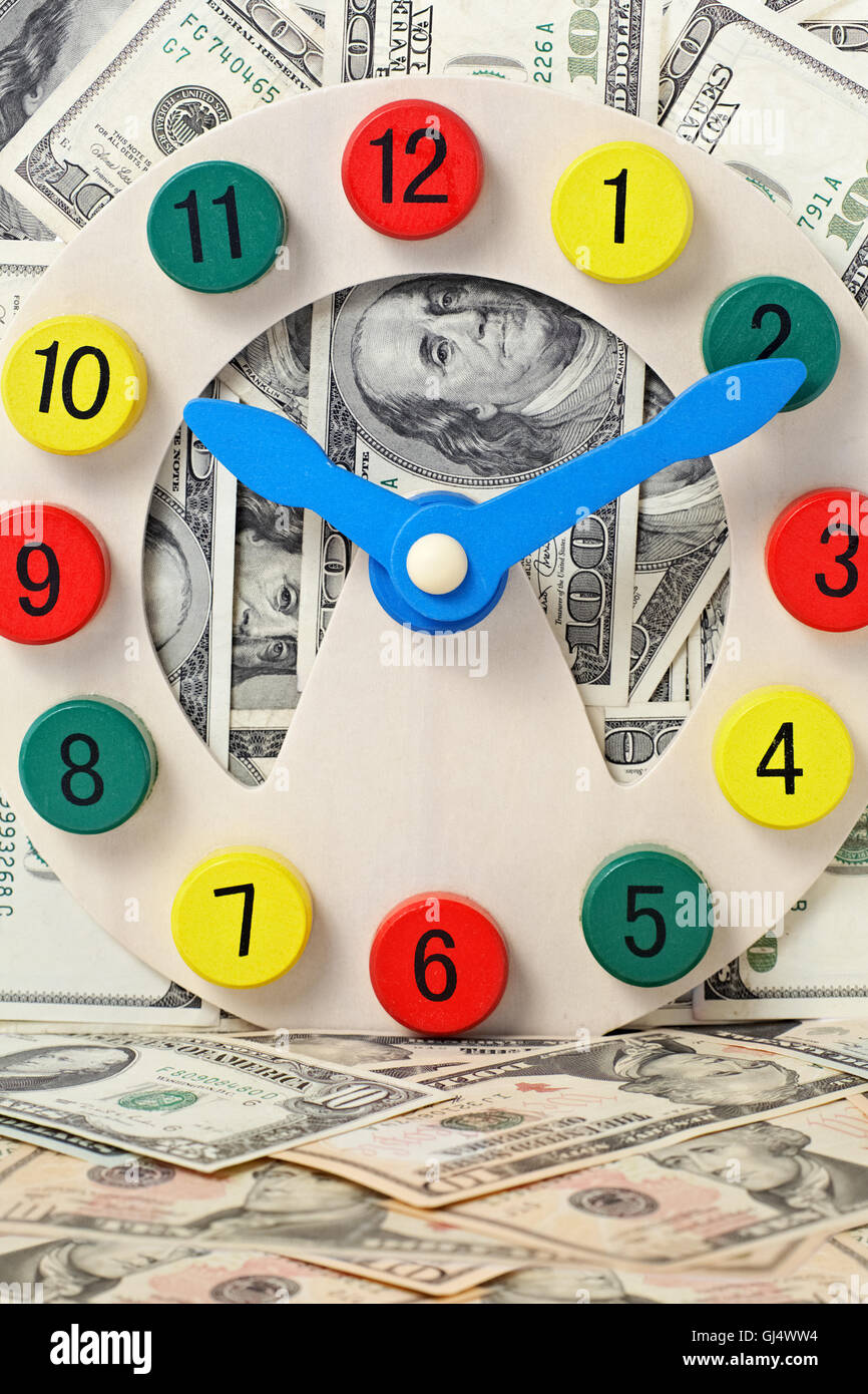 wooden clock on dollars background Stock Photo - Alamy
