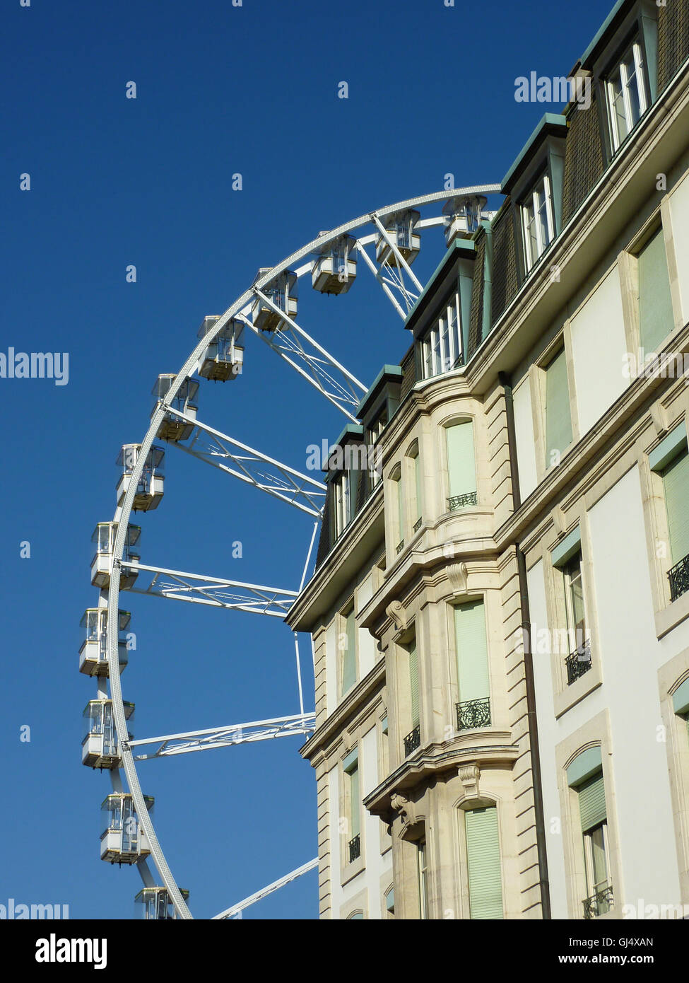 Wheel roundabout behind old white building Stock Photo - Alamy