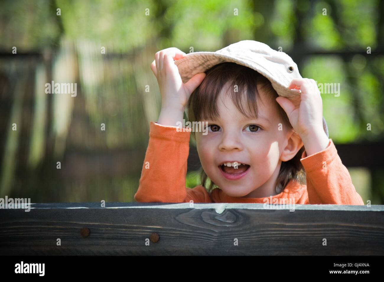 playful child holding his hat Stock Photo - Alamy