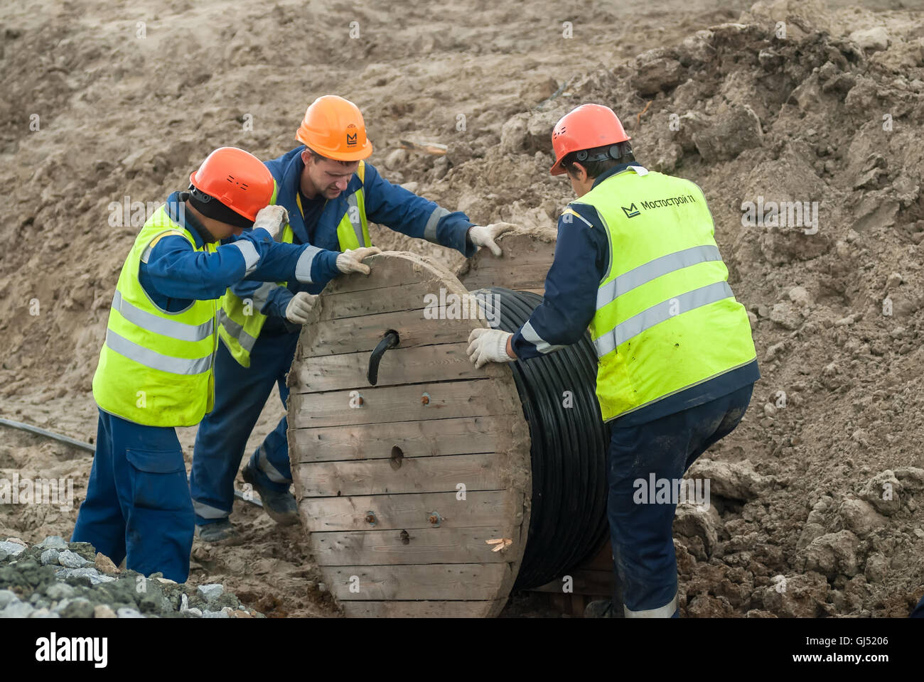 Workers pulling roll high voltage cable line Stock Photo - Alamy