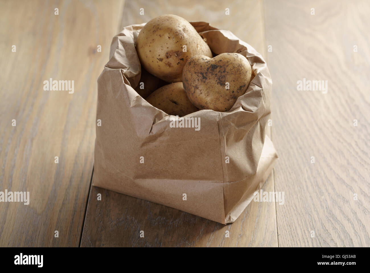 fresh potatoes in kraft paper bag on oak table Stock Photo - Alamy