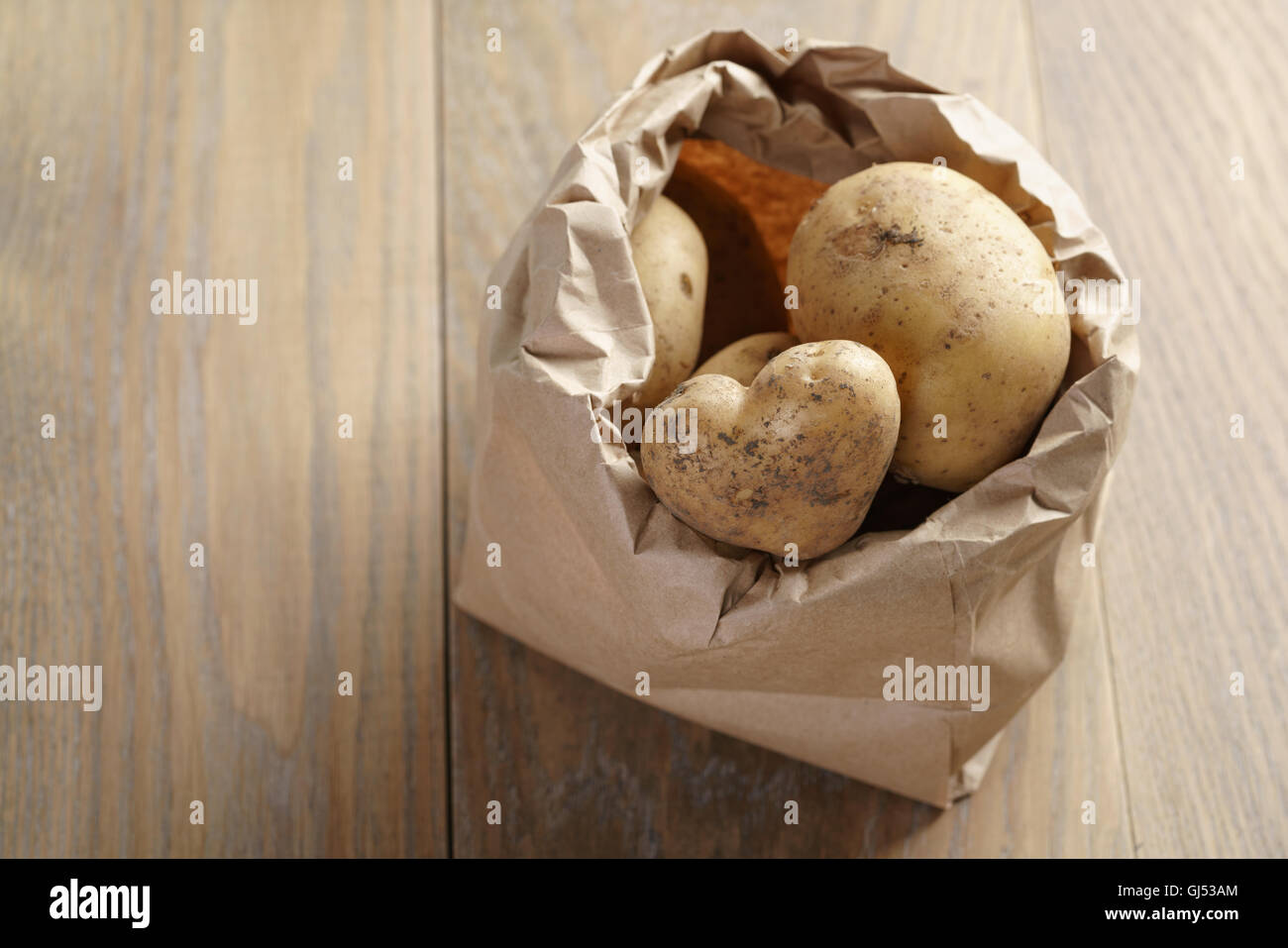 fresh potatoes in kraft paper bag on oak table Stock Photo - Alamy