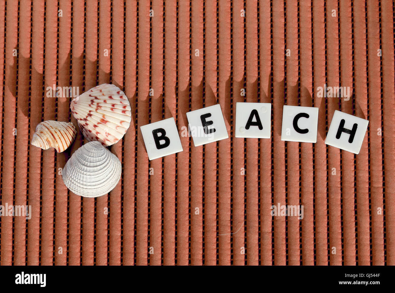 "Beach" letter tiles and sea shells still life Stock Photo - Alamy