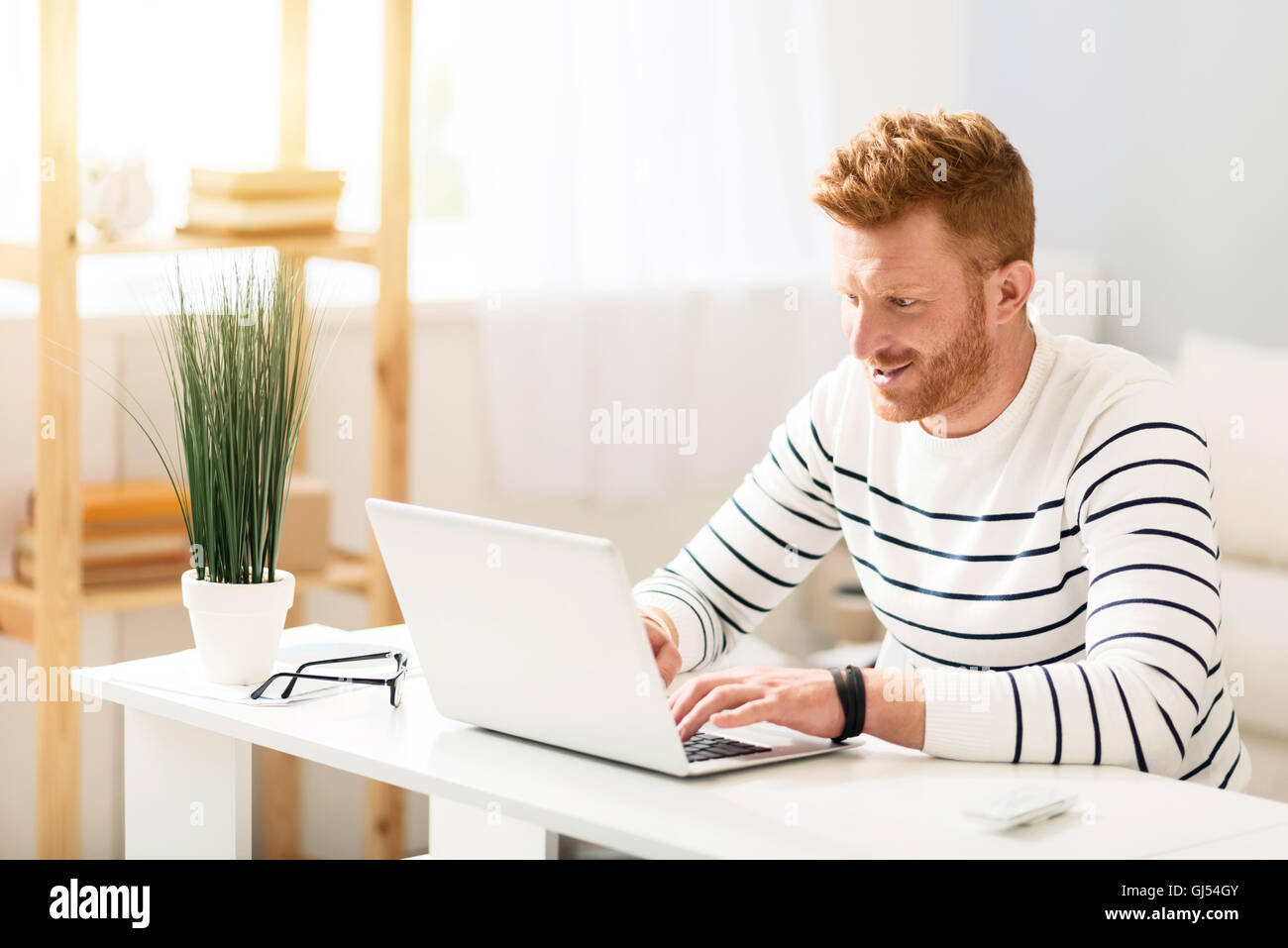 Cheerful involved man using laptop Stock Photo - Alamy