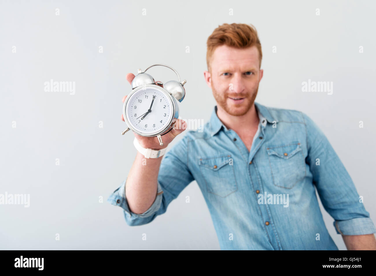 Positive man holding alarm clock Stock Photo - Alamy