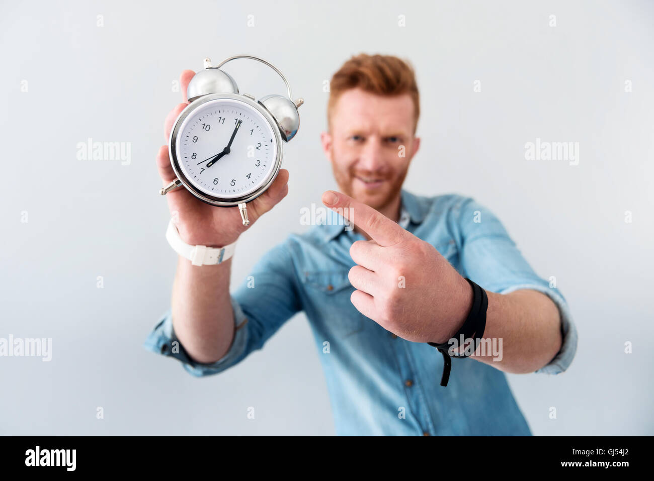 Smiling man holding alarm clock Stock Photo - Alamy