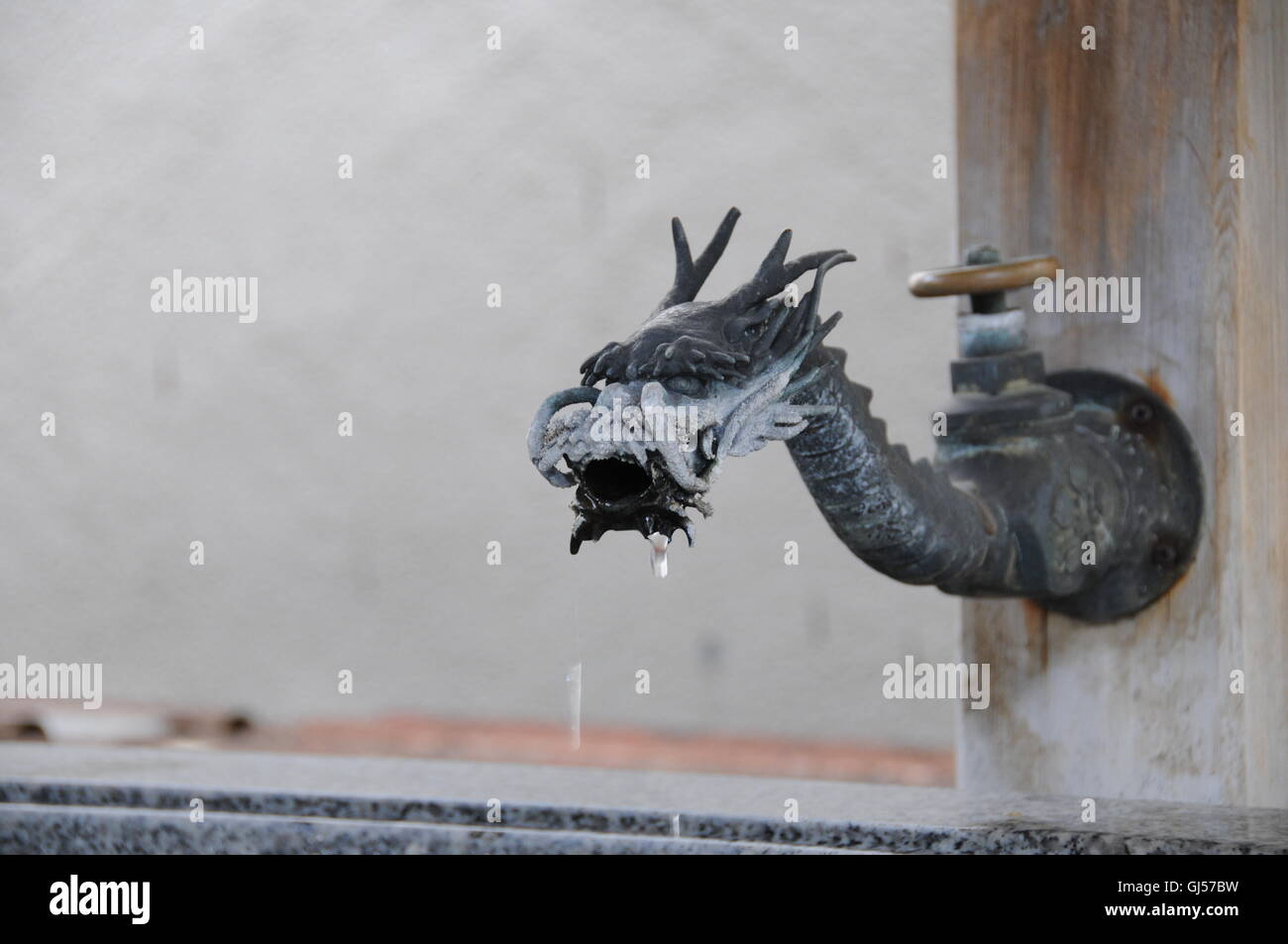 Bronze dragon shaped cold water tap at a Tokyo Shrine entrance with ...