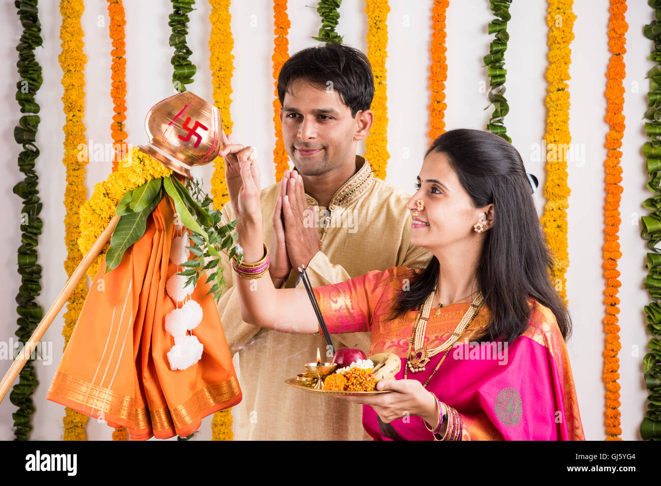 smart indian couple in traditional wear performing gudhi padwa puja ...