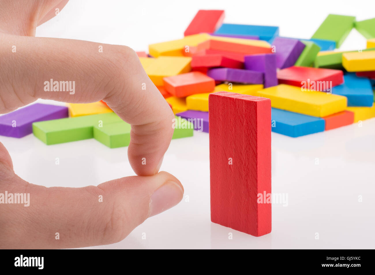 Hand playing with colored domino on white background Stock Photo - Alamy