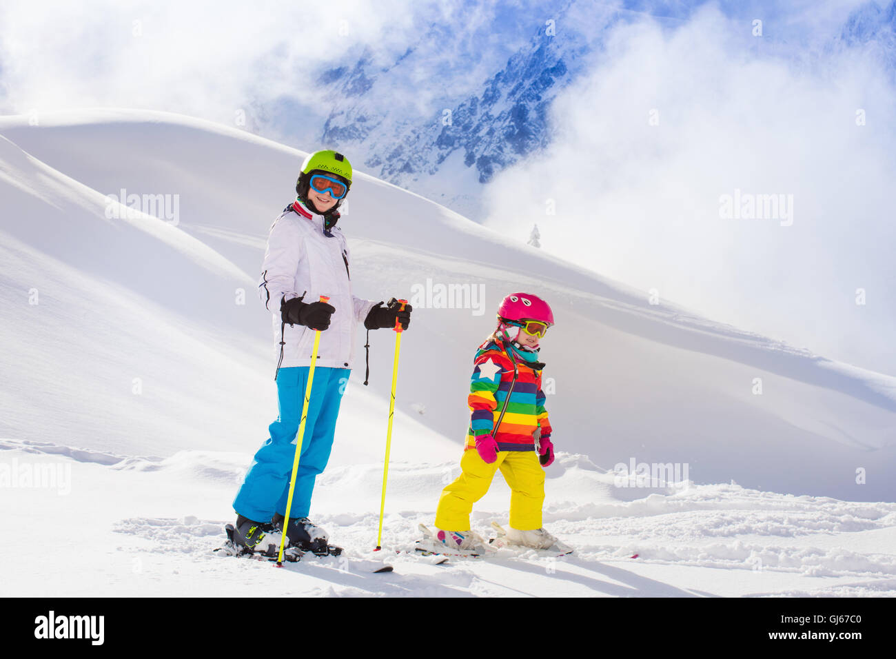Boy and girl skiing in mountains. Toddler kid and teenager with helmet ...