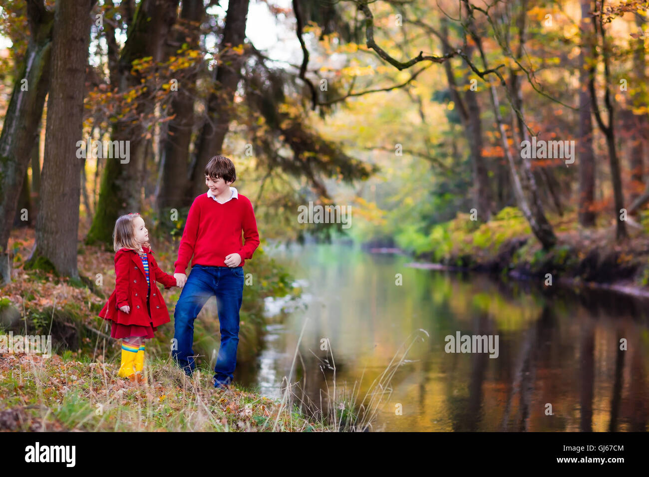 Happy children playing on river shore in beautiful autumn park on warm ...