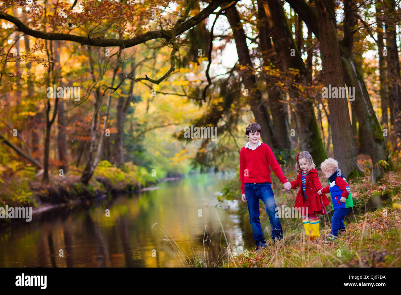 Happy children playing on river shore in beautiful autumn park on warm ...