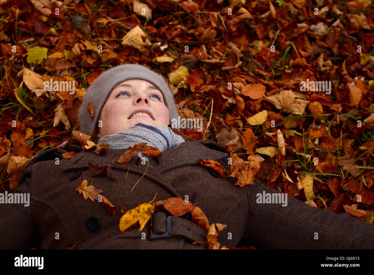 Fall - young woman lying down in leaves Stock Photo - Alamy