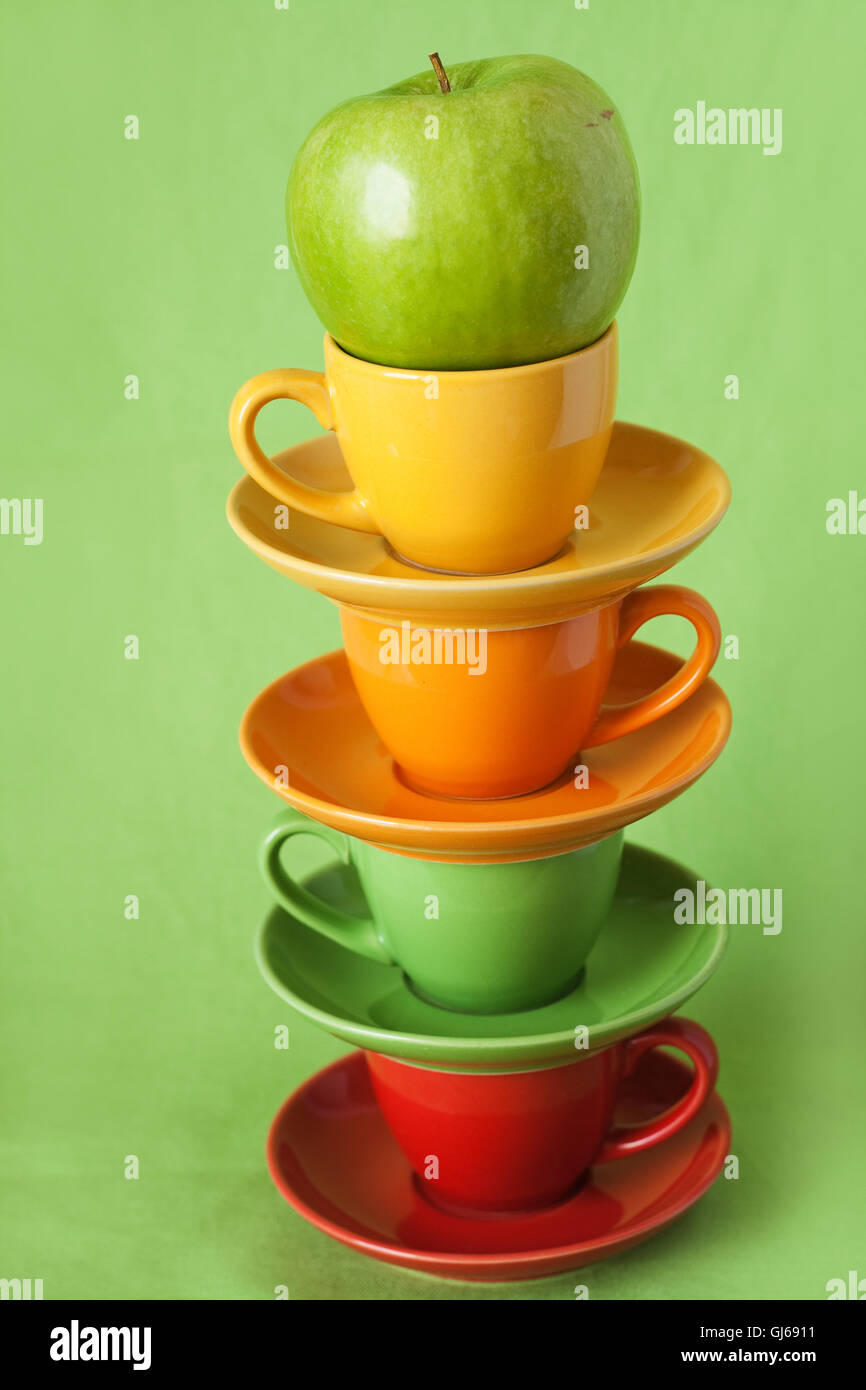 Green apple and bright cups on a green background Stock Photo - Alamy