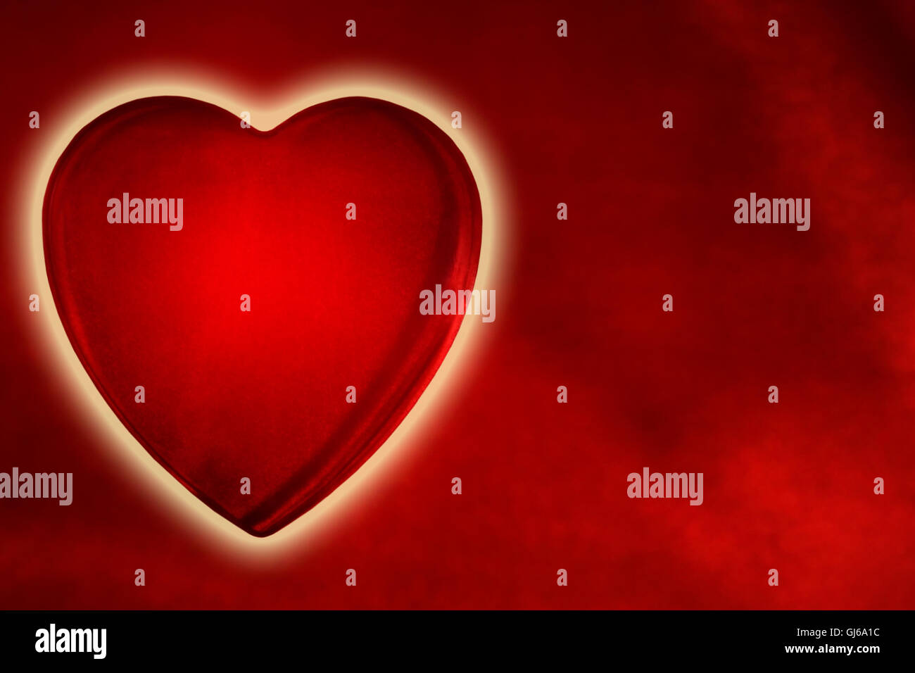 Glowing love heart on red silk Stock Photo - Alamy