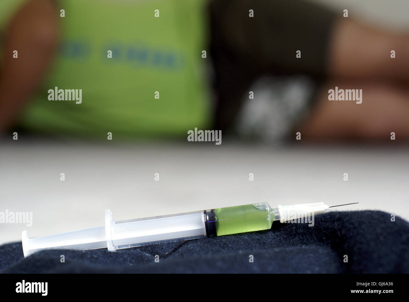 Unconscious addict and syringe on floor in foreground Stock Photo - Alamy