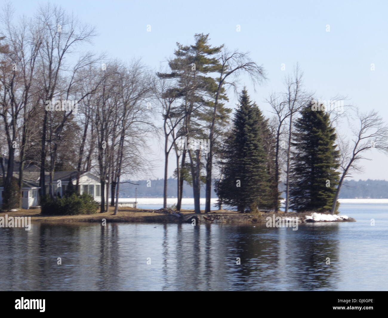A small peninsula of land with trees jutting out into a small lake ...