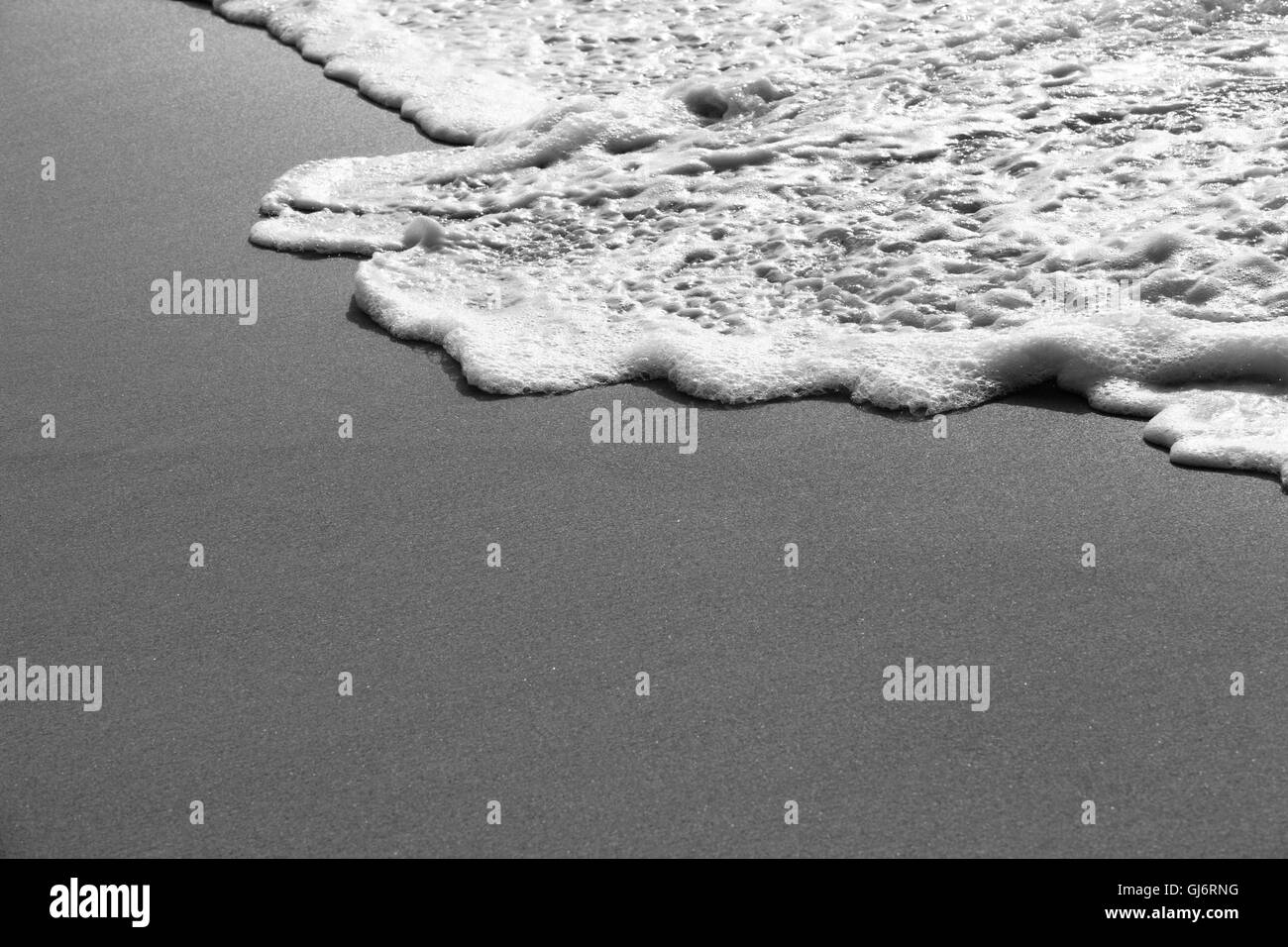 wave on the sand with white crest Stock Photo - Alamy