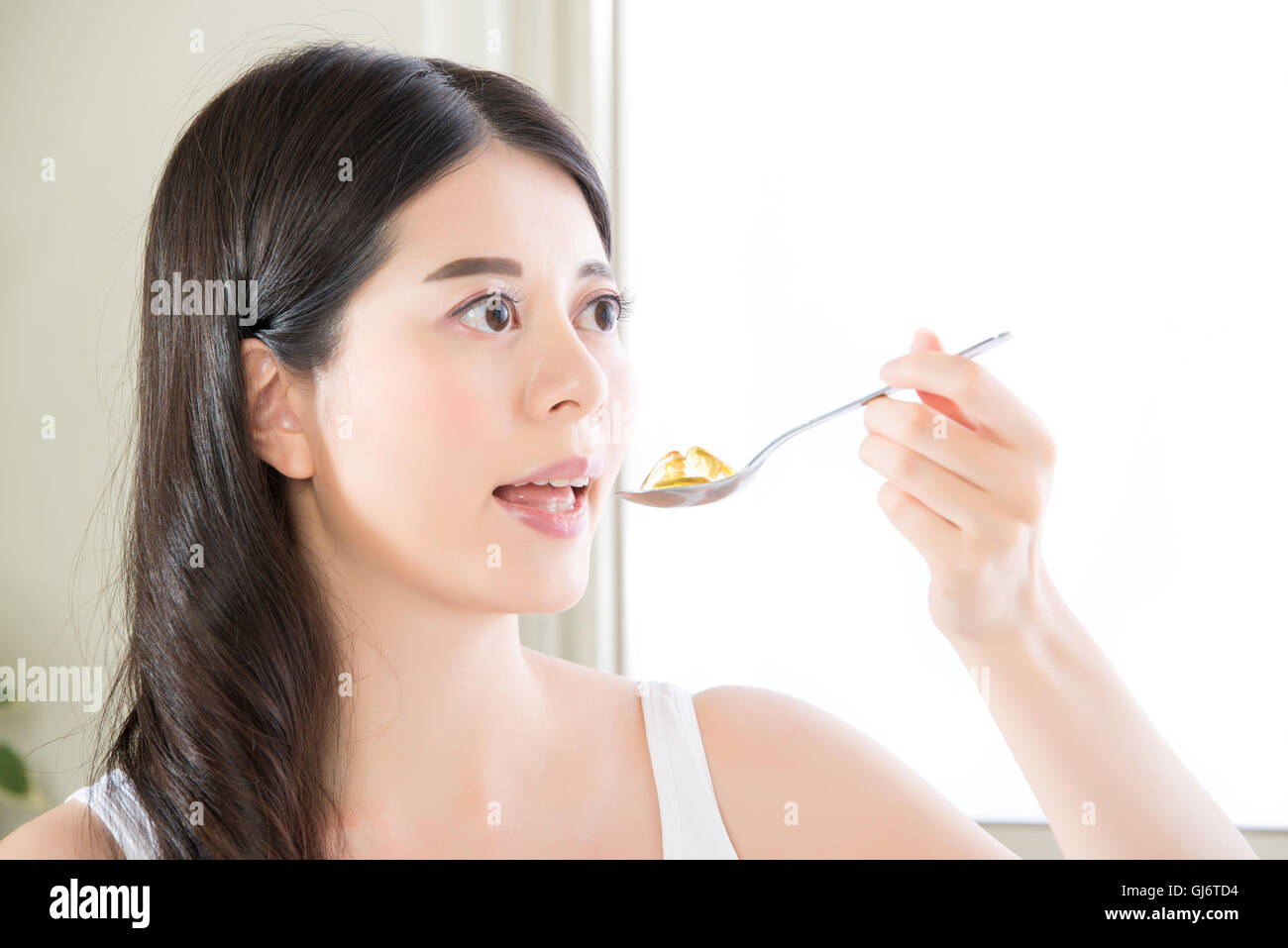 young beautiful asian woman eating nutritional supplement pill for ...