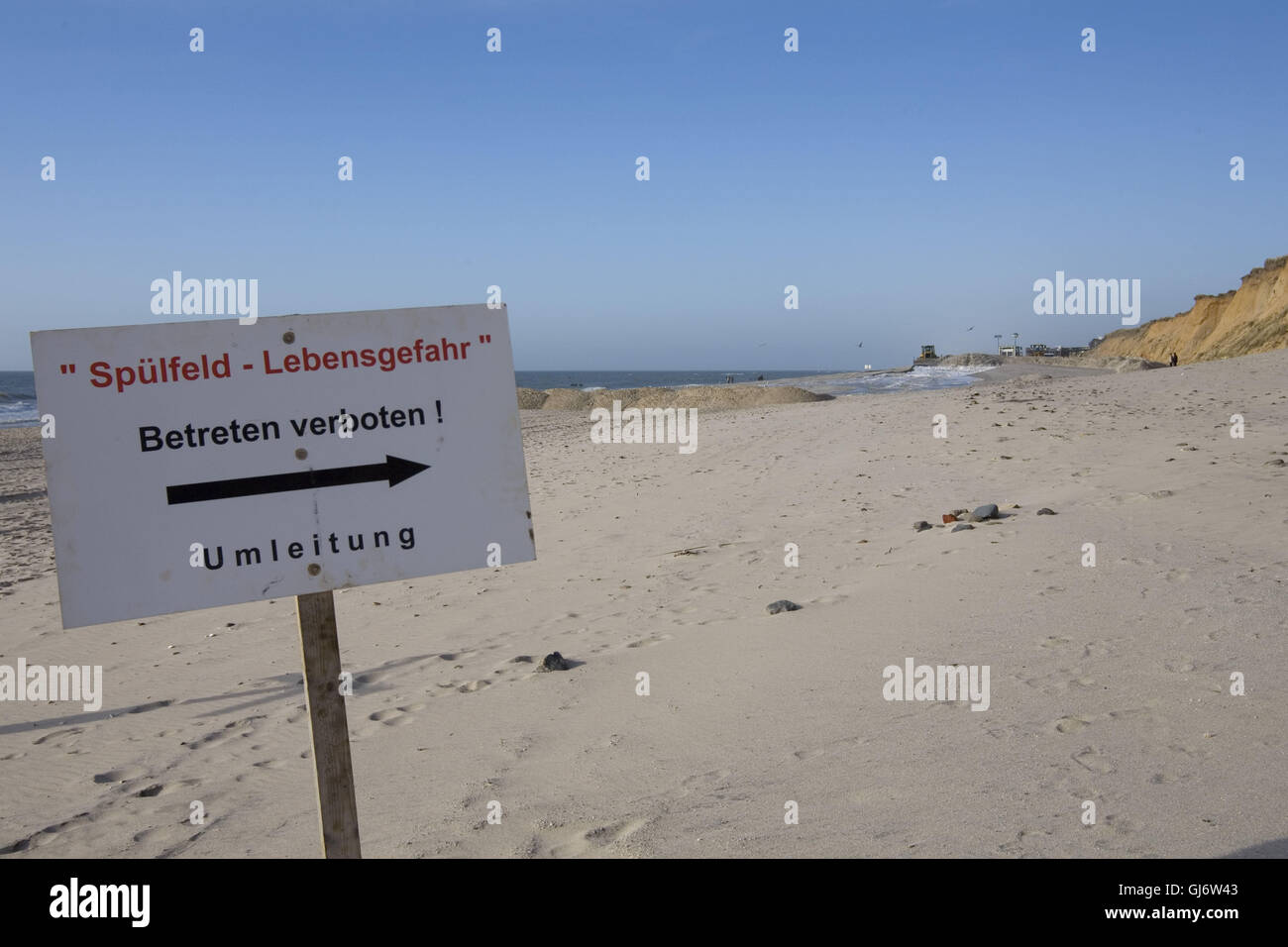 Sand replenishment at the red cliff, sign Stock Photo - Alamy