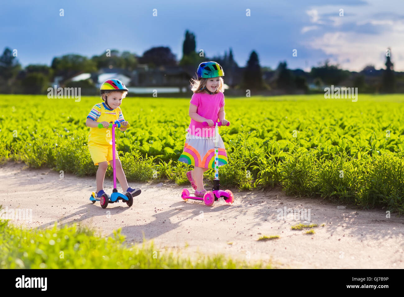 Children learn to ride scooter in a park on sunny summer day ...