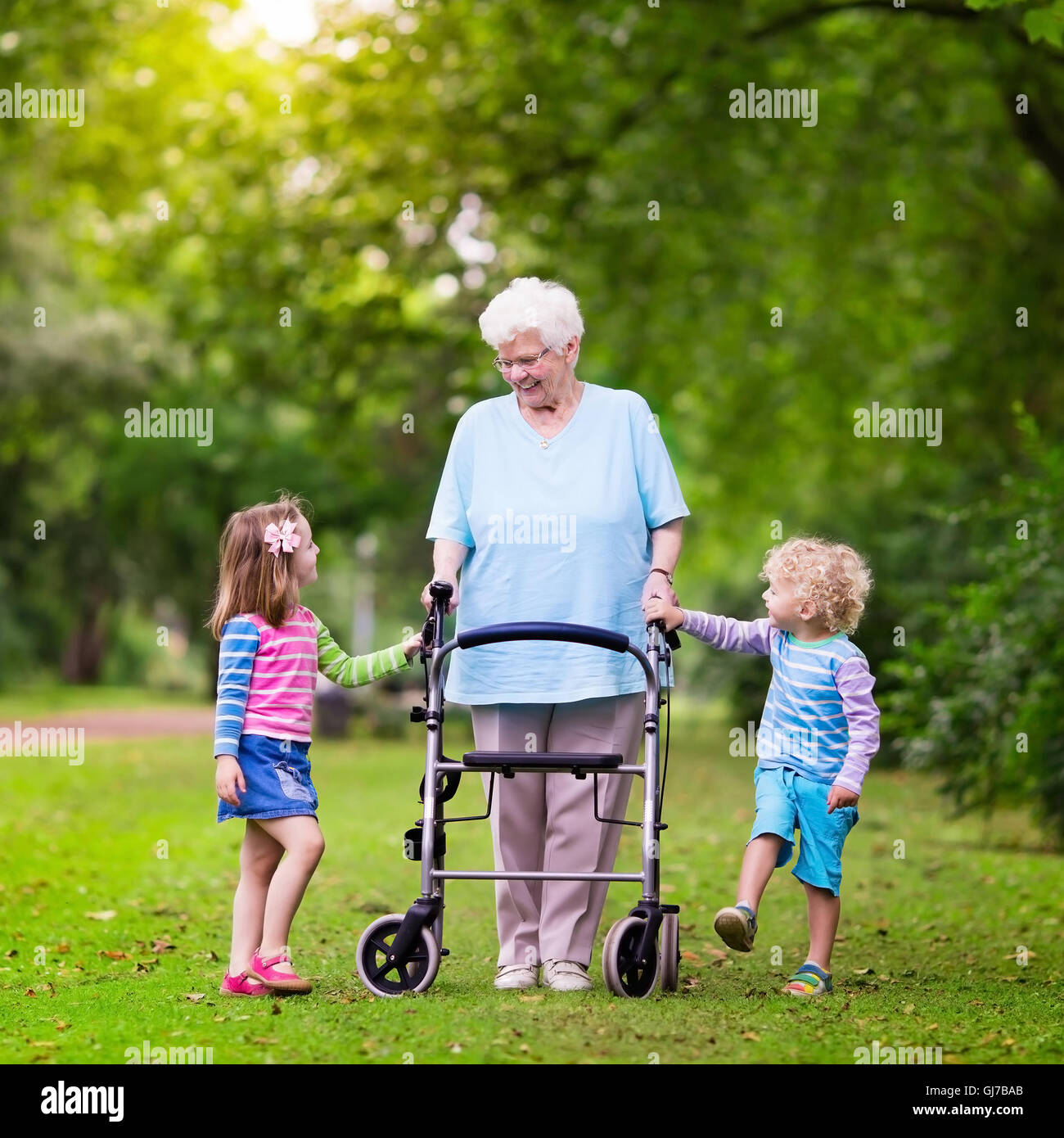 Happy senior lady with a walker holding hands of little boy and girl ...