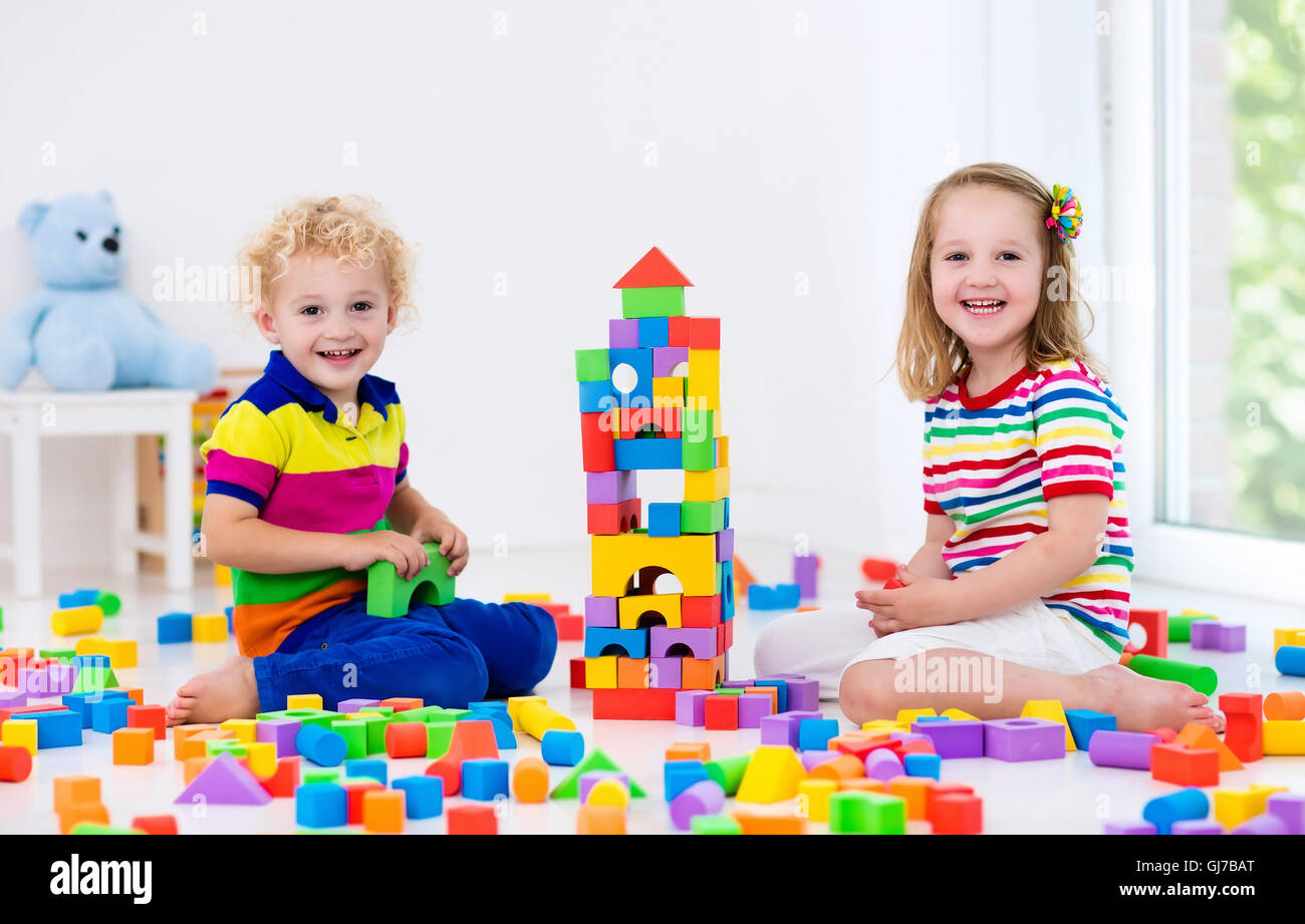 Happy preschool age children play with colorful plastic toy blocks ...