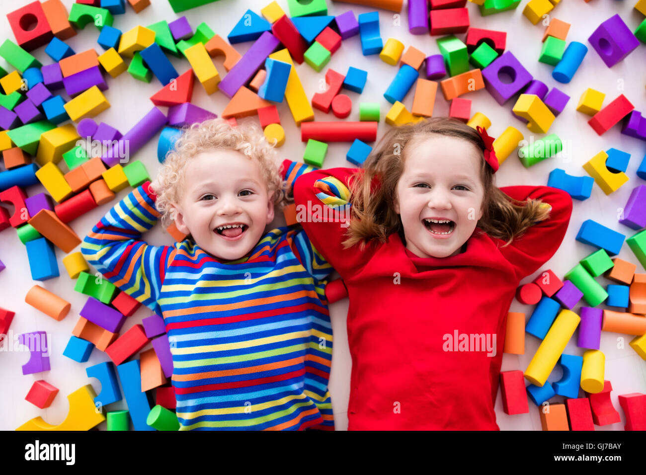 Happy preschool age children play with colorful plastic toy blocks ...