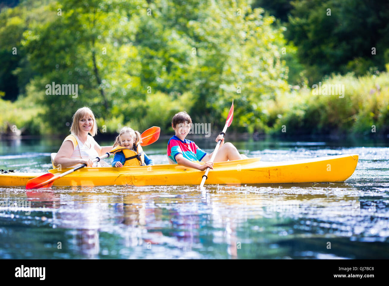 Happy family with two kids enjoying kayak ride on beautiful river ...