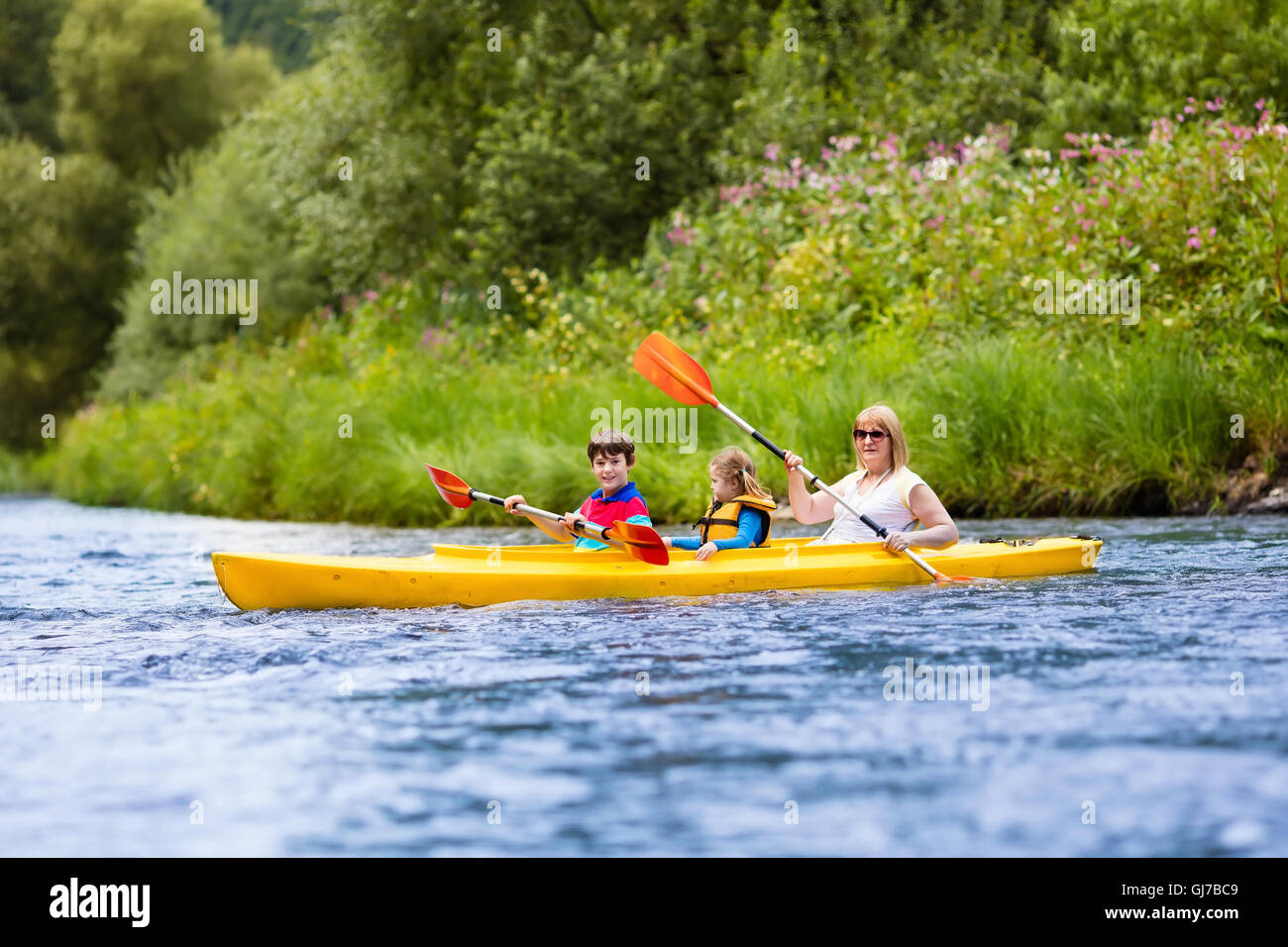 Happy family with two kids enjoying kayak ride on beautiful river ...