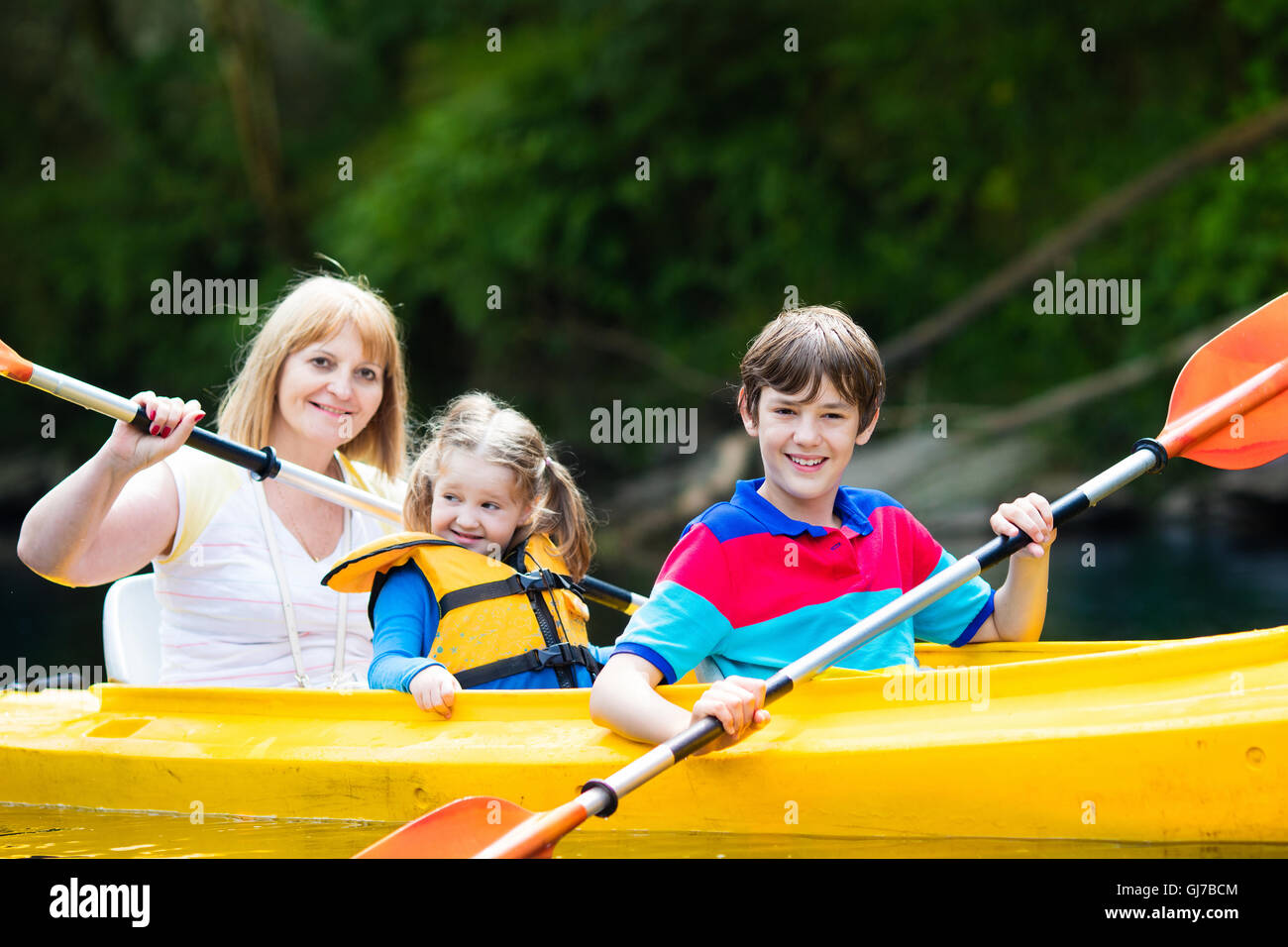 Happy family with two kids enjoying kayak ride on beautiful river ...