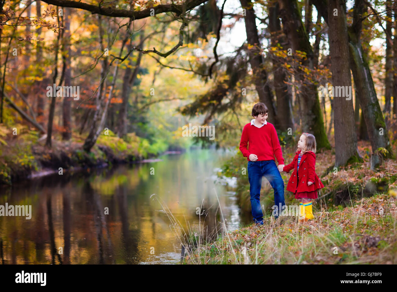 Happy children playing on river shore in beautiful autumn park on warm ...