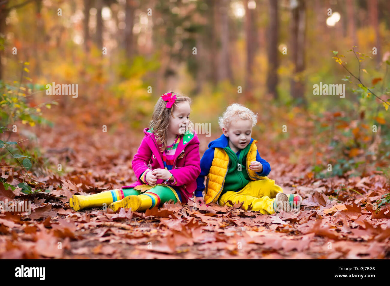 Happy children playing in beautiful autumn park on cold sunny fall day ...