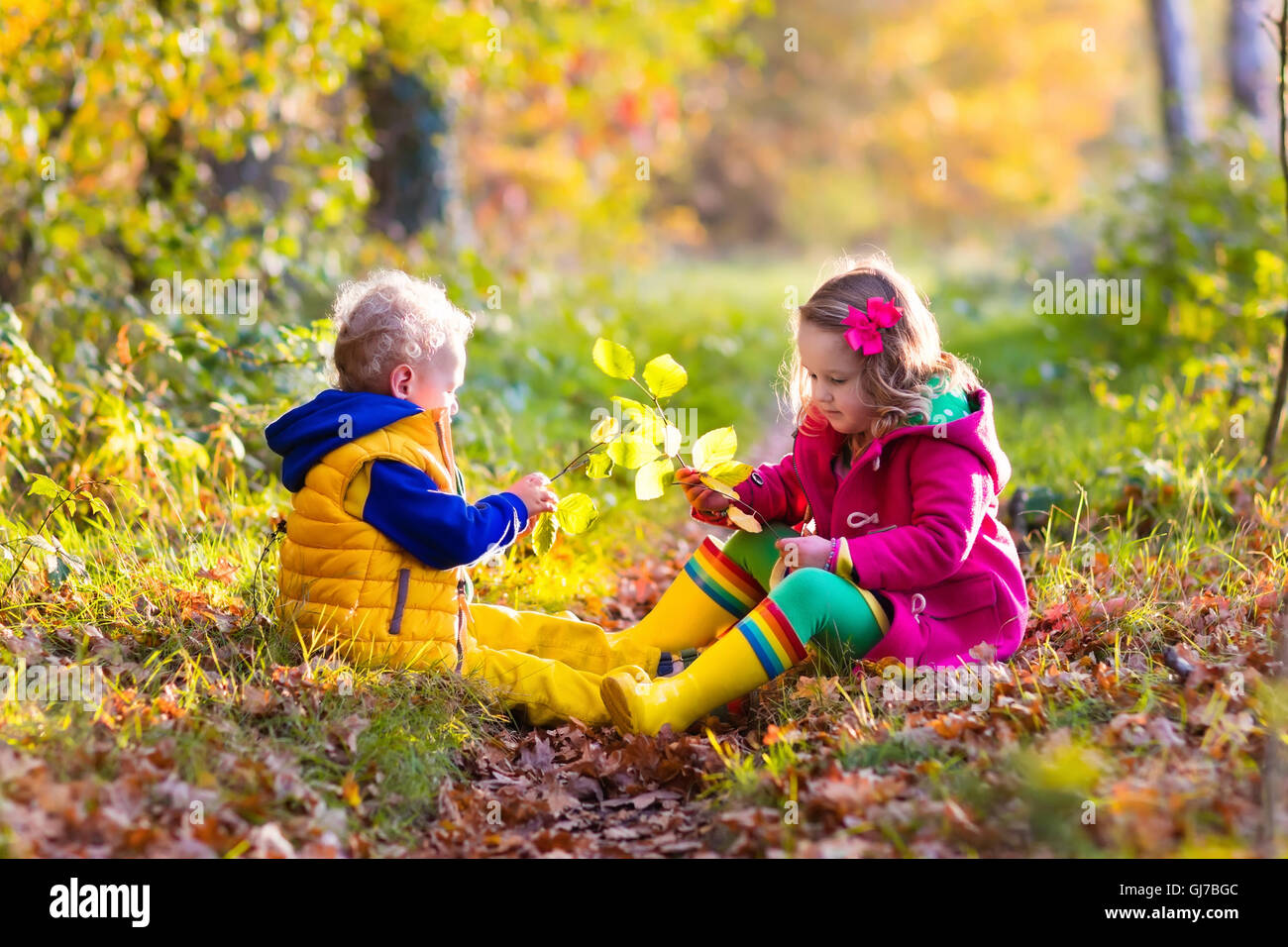 Happy children playing in beautiful autumn park on cold sunny fall day ...