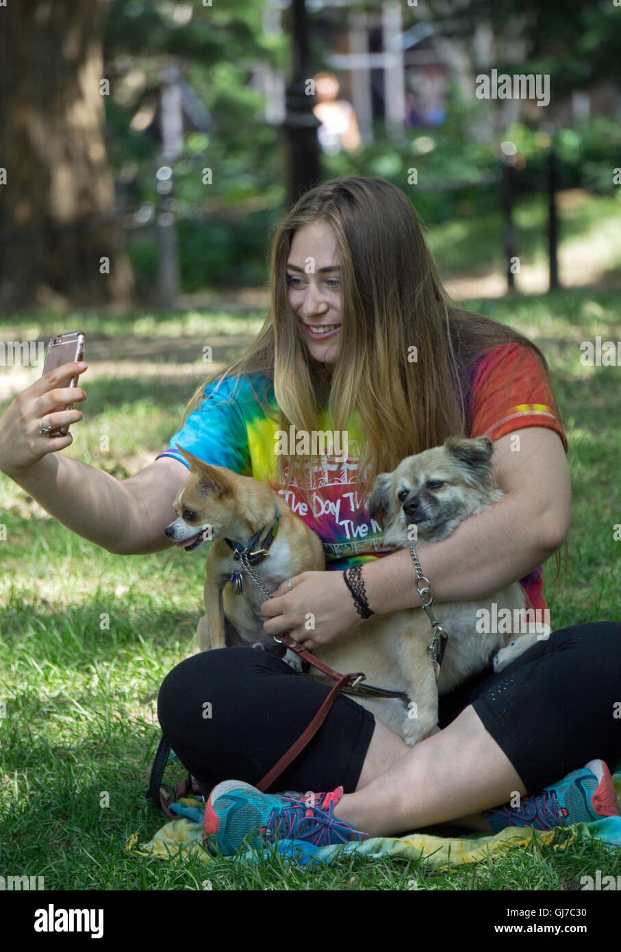 A happy lady takes a selfie with her two pet dogs in Washington Square ...