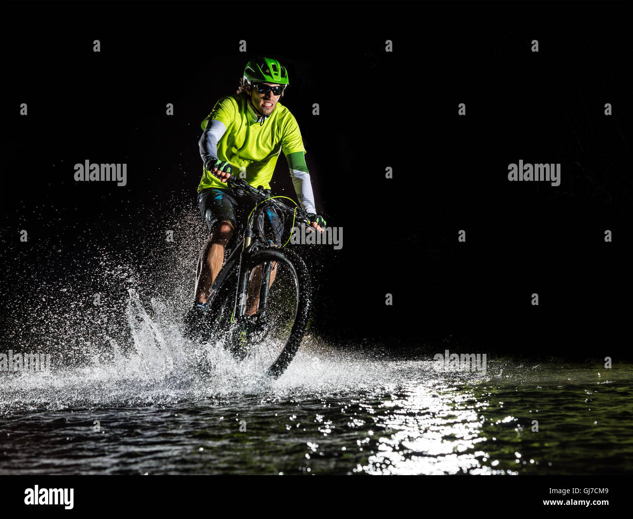 Mountain biker riding in forest stream, splashing water around Stock ...
