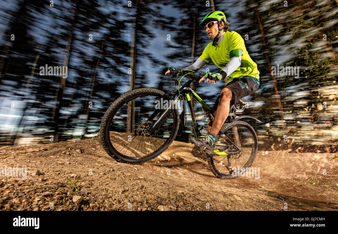 Low angle view of mountain biker riding on rocky trail at sunset Stock ...