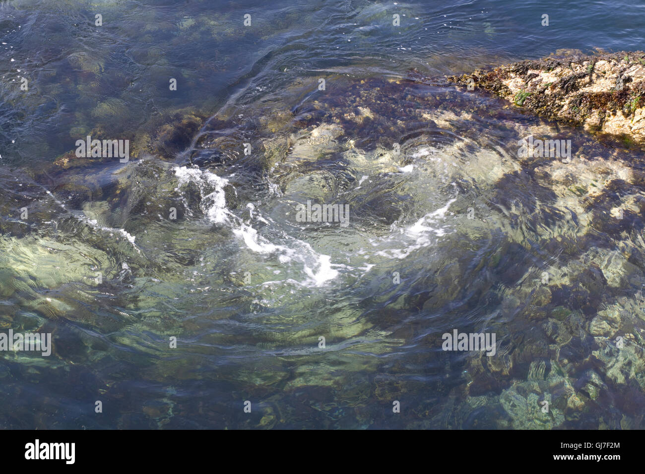 water swirling over rocks in the ocean Stock Photo - Alamy