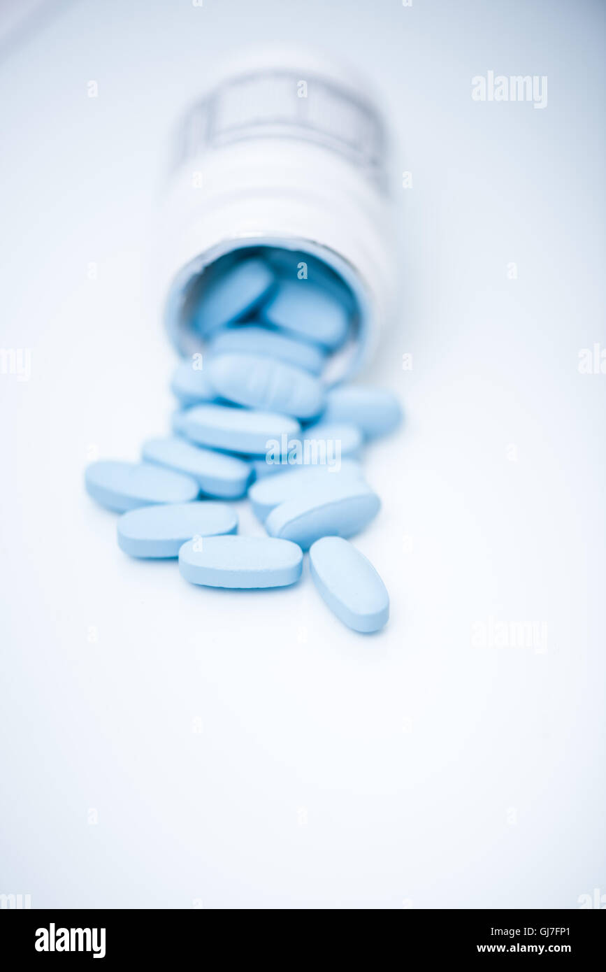 blue pills from container on white background Stock Photo - Alamy