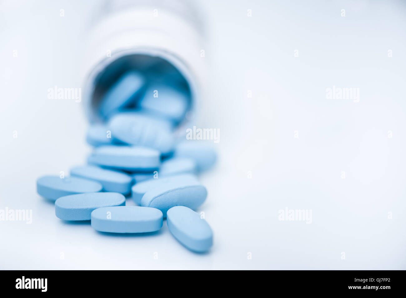 blue pills from container on white background Stock Photo - Alamy