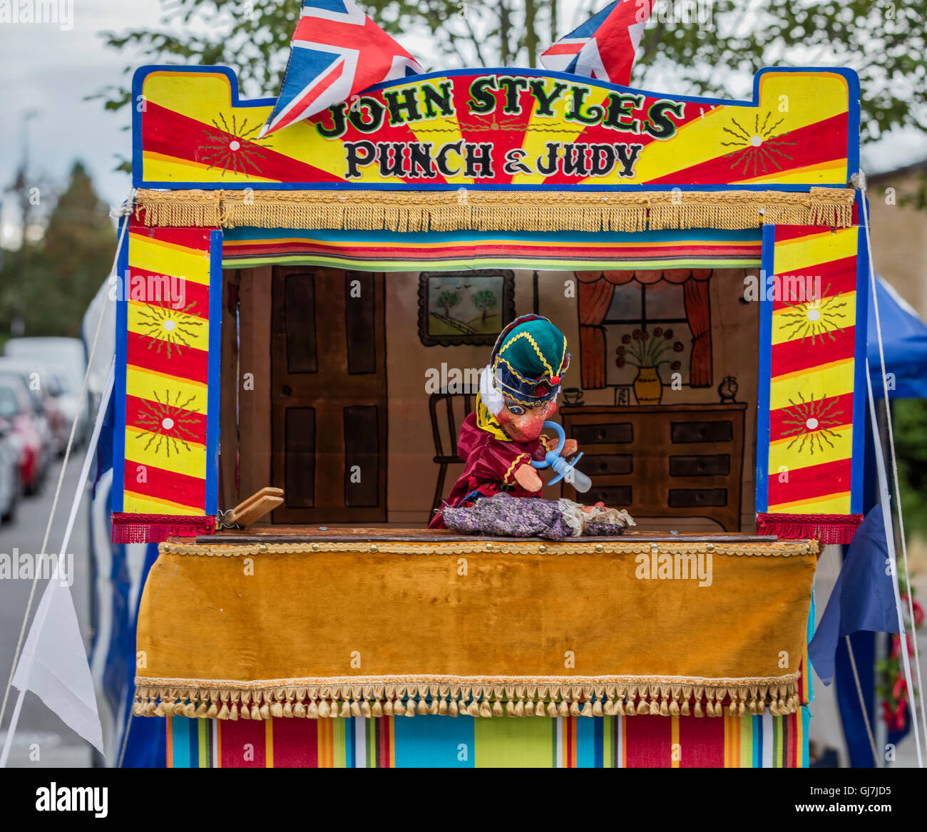 Mr Punch gives the baby a plastic dummy in front of a Punch and Judy ...