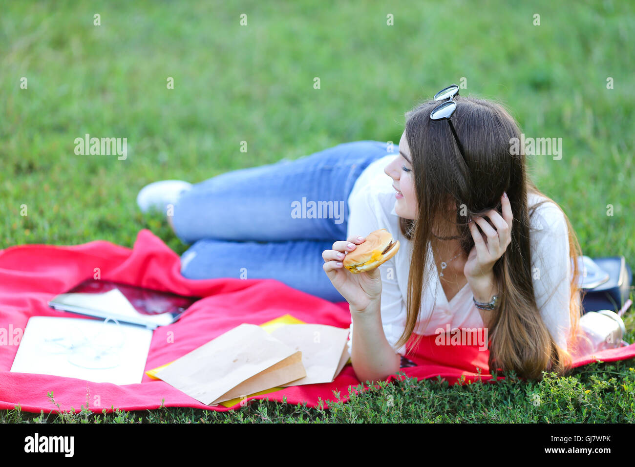 girl lying on the nature and eateth fast food. student working in the ...