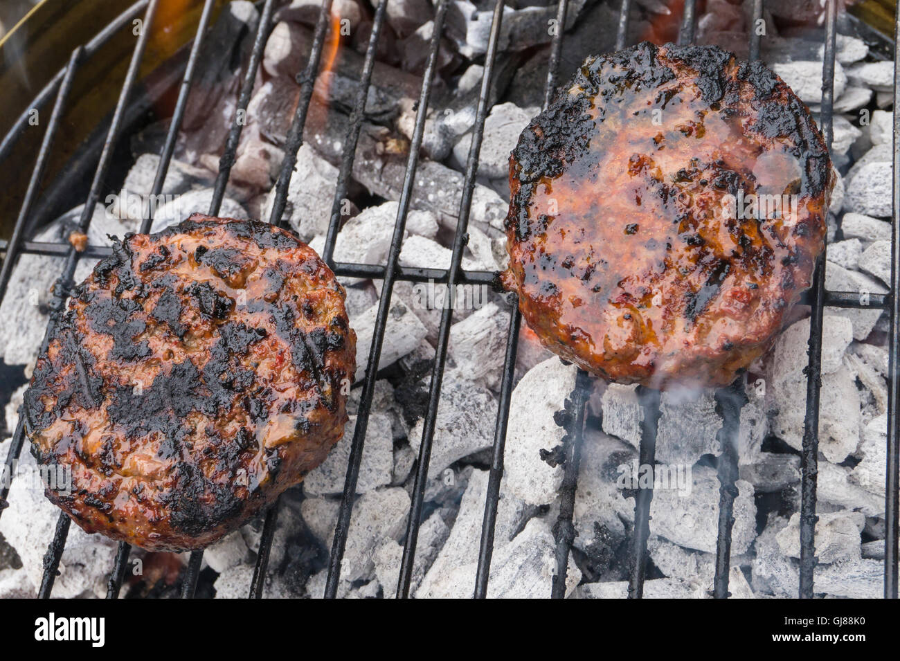 Burgers cooking on a barbecue grill Stock Photo - Alamy