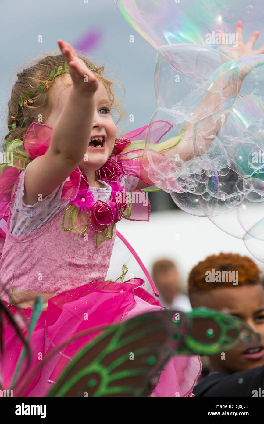 Burley, Hampshire, UK. 13th Aug, 2016. Young girl dressed as fairy catching bubbles at the New ...