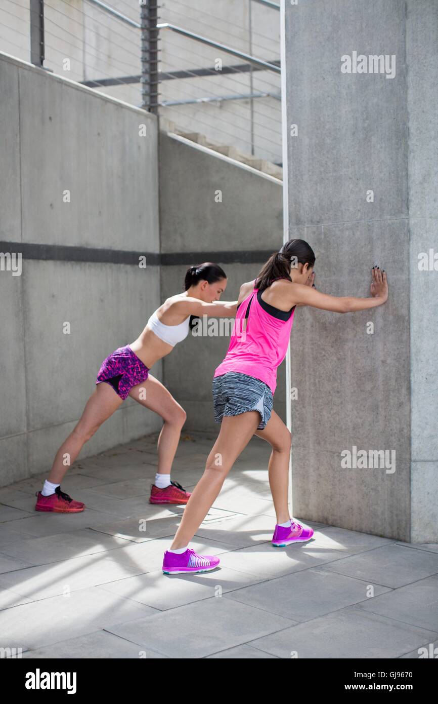 MODEL RELEASED. Two young women stretching against wall Stock Photo - Alamy