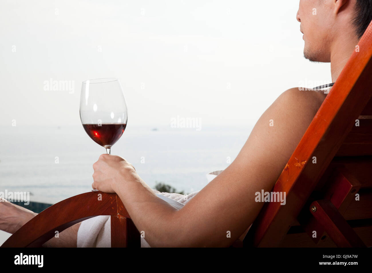 Young men lounge by the pool drinking wine Stock Photo - Alamy